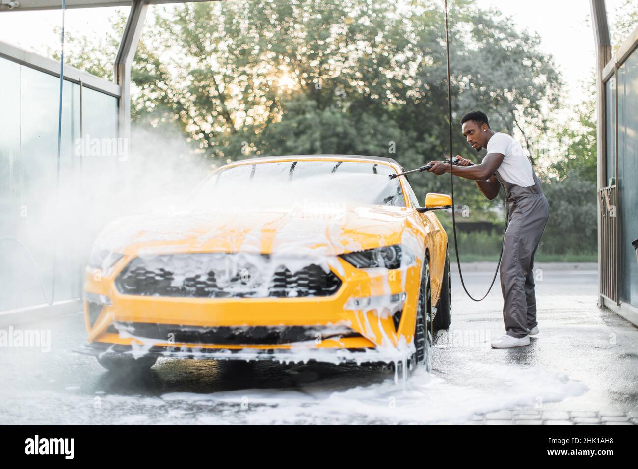 African stylish young focused man in work clothes washing his modern ...