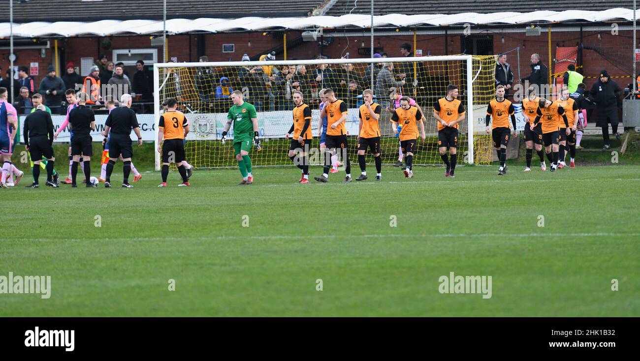 The referee leads the linesmen and teams on to the field for a football ...