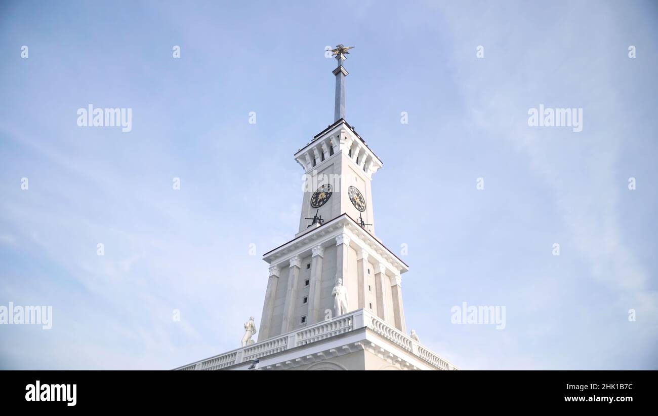 White clock tower on background of blue sky. Action. Bottom view of ...