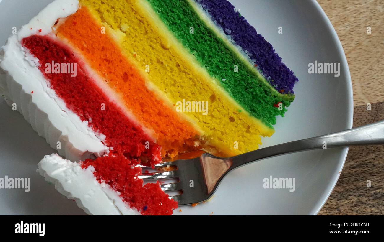 Getting a forkful of rainbow pride cake Stock Photo - Alamy
