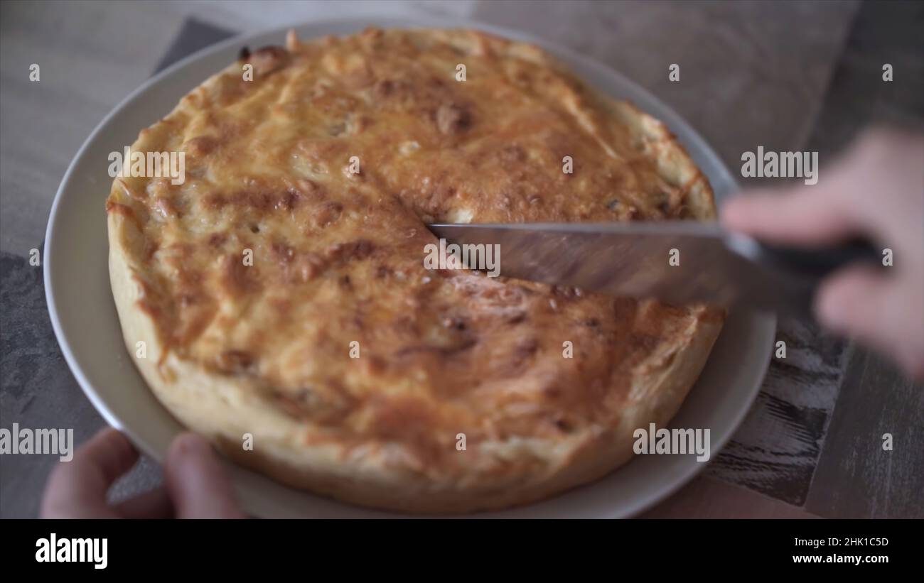 Close up of hands cutting freshly baked pie lying on a glass plate in ...