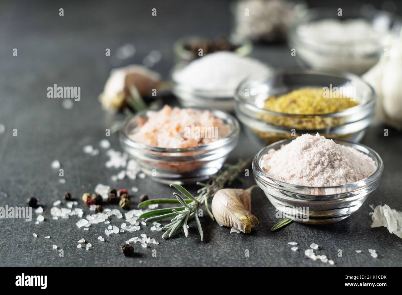 Different types of salt and culinary spices in glass plates on a dark ...