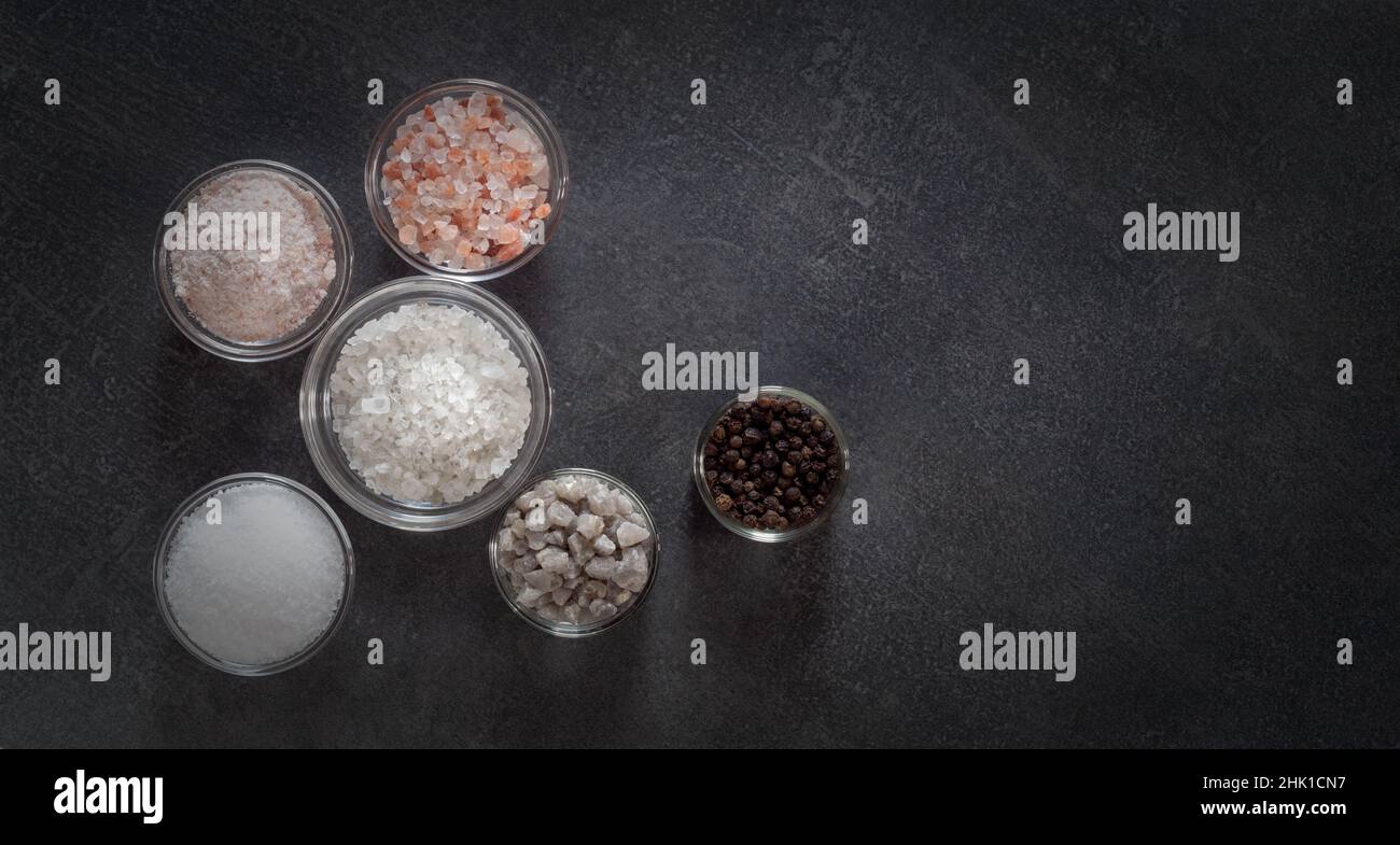 Different types of salt and culinary spices in glass plates on a dark ...