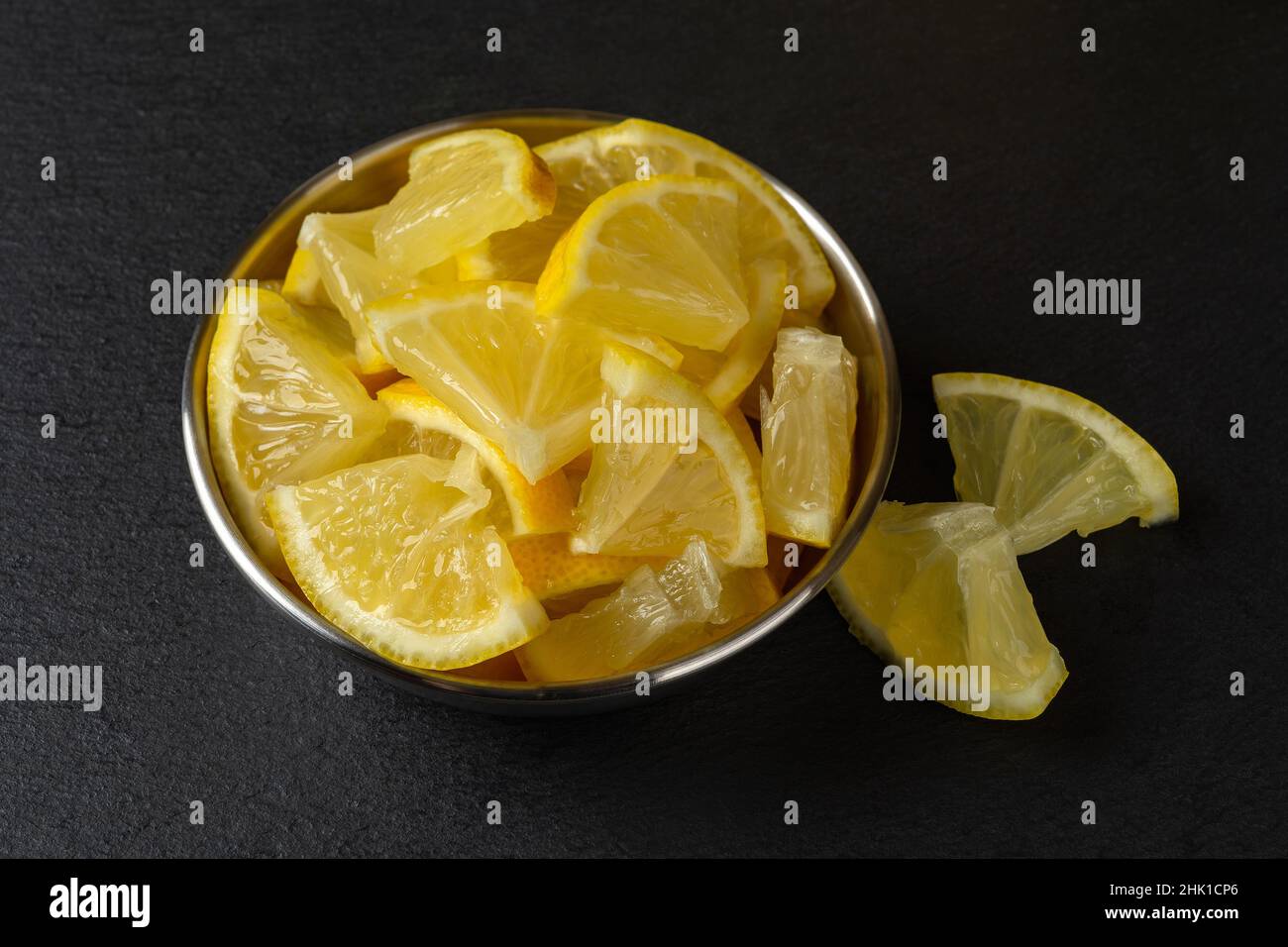 Fresh cutted lemon slices in a metal bowl on a black slate slab. Sliced ...