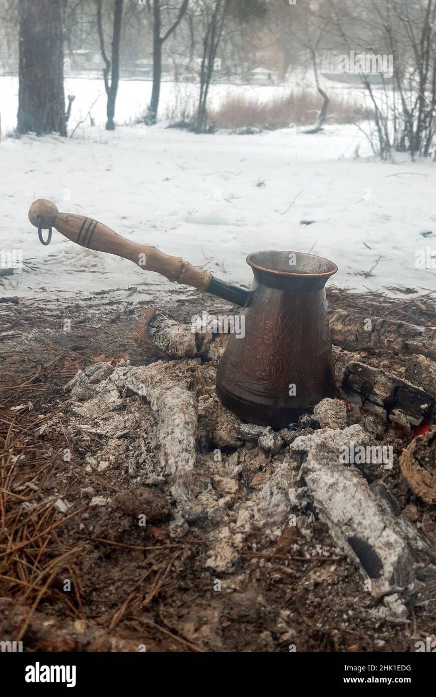 Copper cezve with coffee is cooked on the hot coals of a fire in a ...