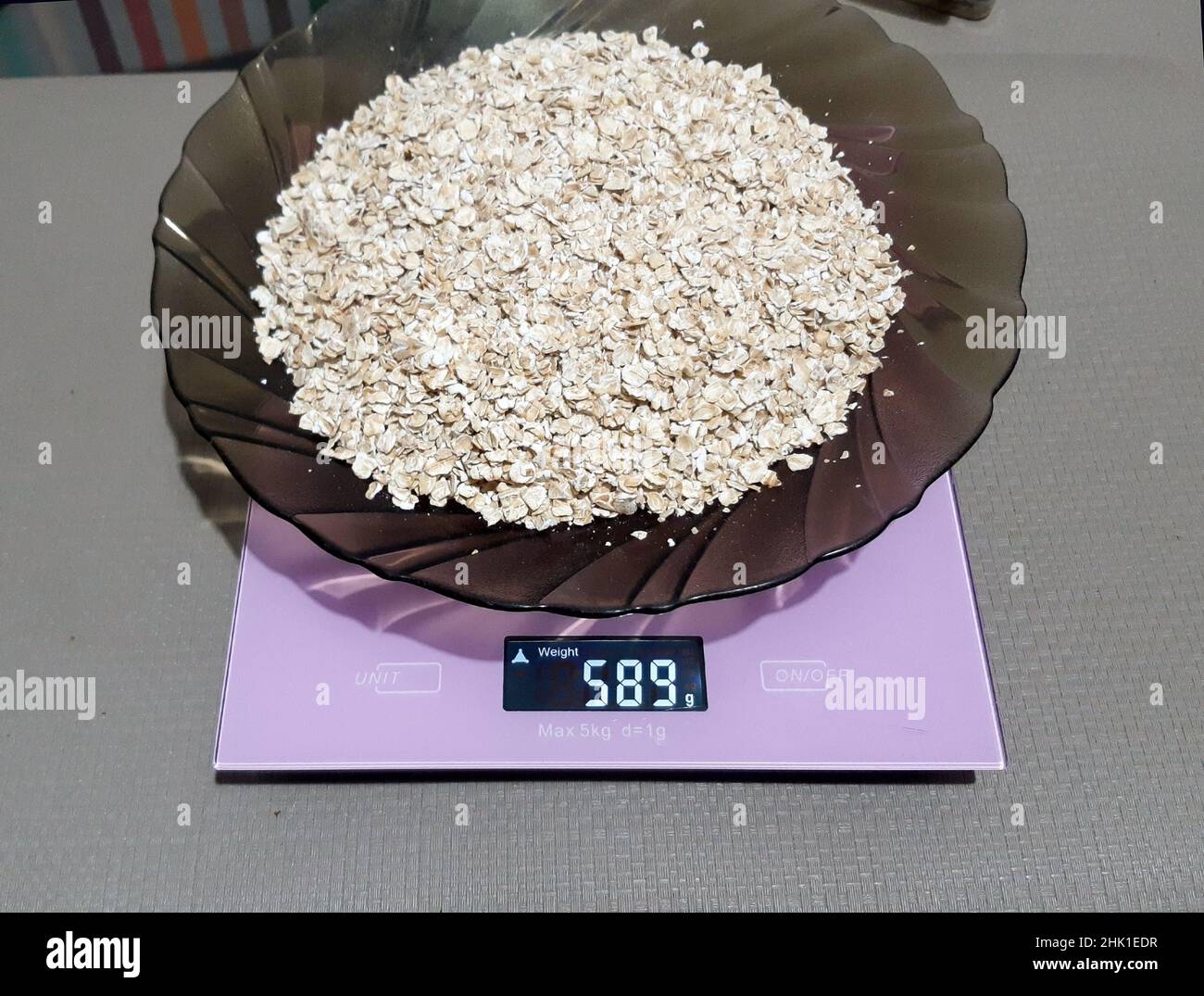 A plate of raw oatmeal stands on an electronic scale to measure the ...