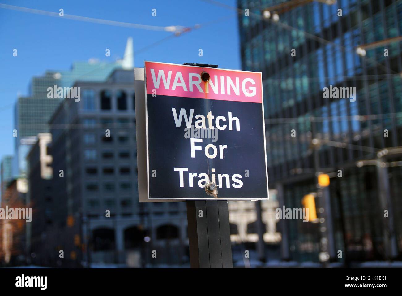 Warning Watch for Trains black and red sign with buildings on the back ...