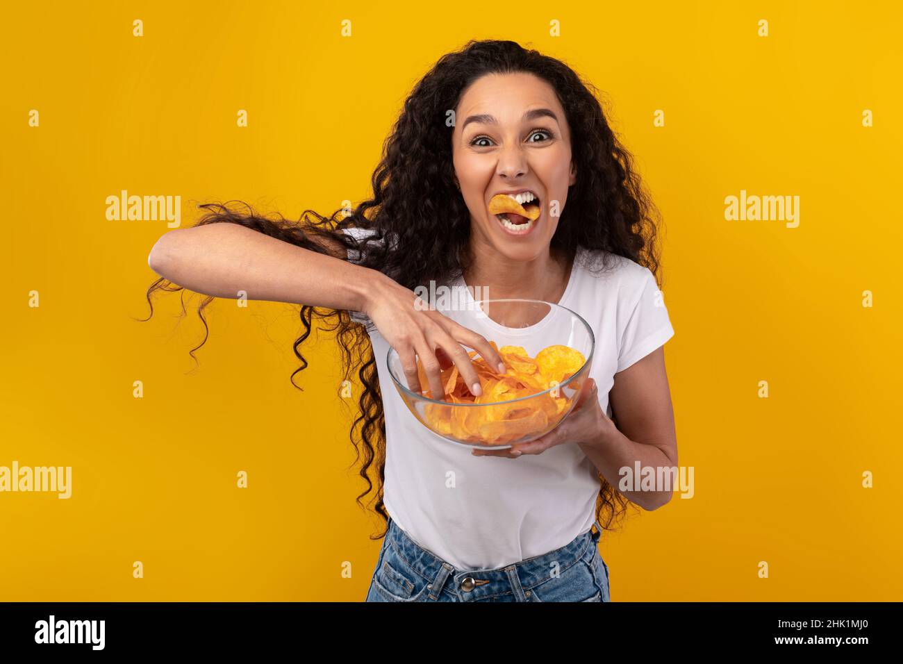 Excited Latin Lady Eating Delicious Potato Crisps Stock Photo - Alamy