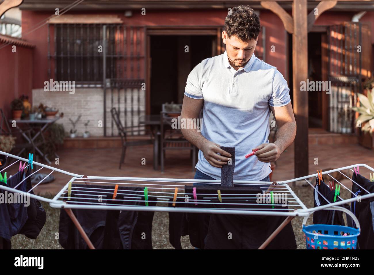 a man hanging out clothes in the garden of his house Stock Photo - Alamy