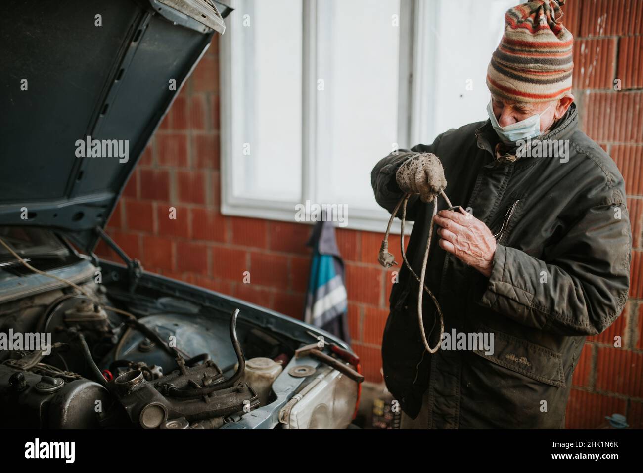 Old man with protective mask in the garage repair his old car Stock ...