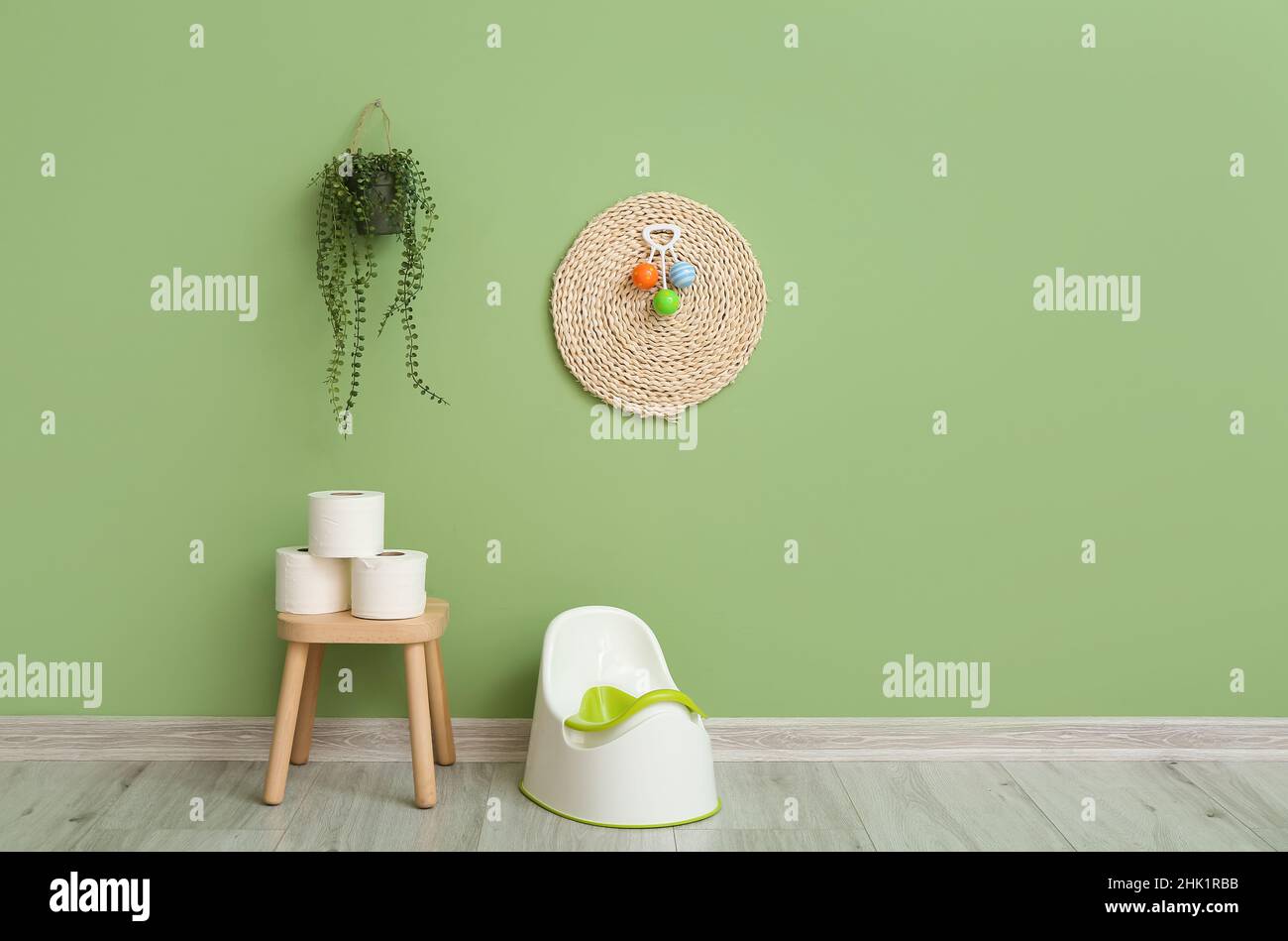 White potty, wooden stool with toilet paper rolls and houseplant near ...