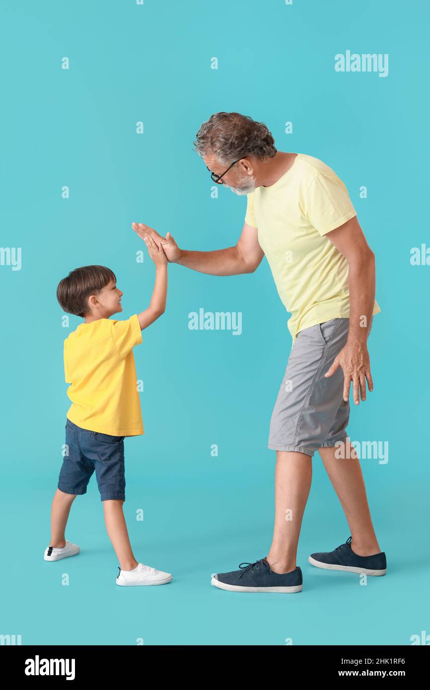 Little boy giving high-five to his grandfather on blue background Stock ...