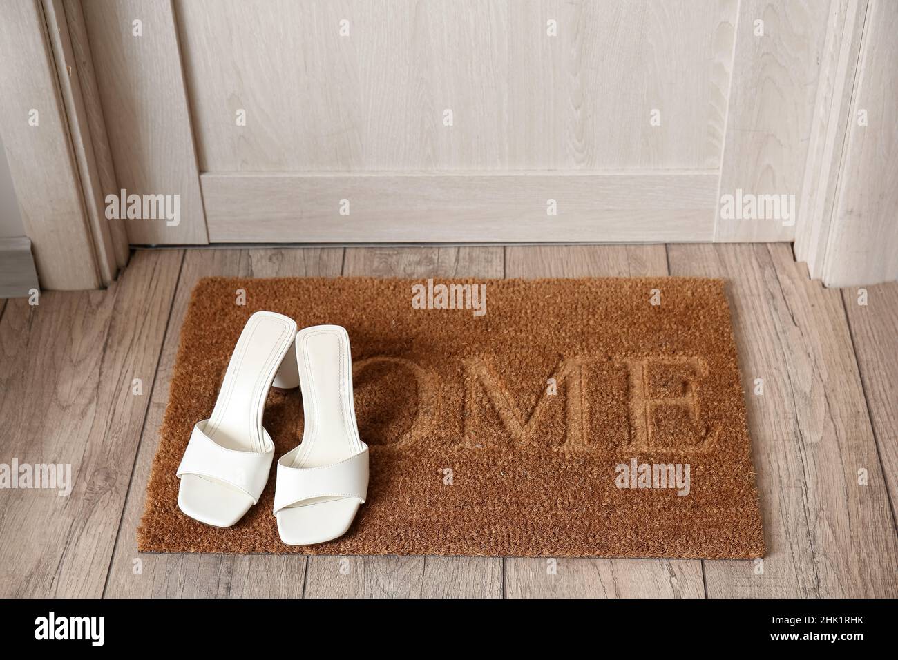 Female shoes on mat near wooden door in hallway Stock Photo - Alamy