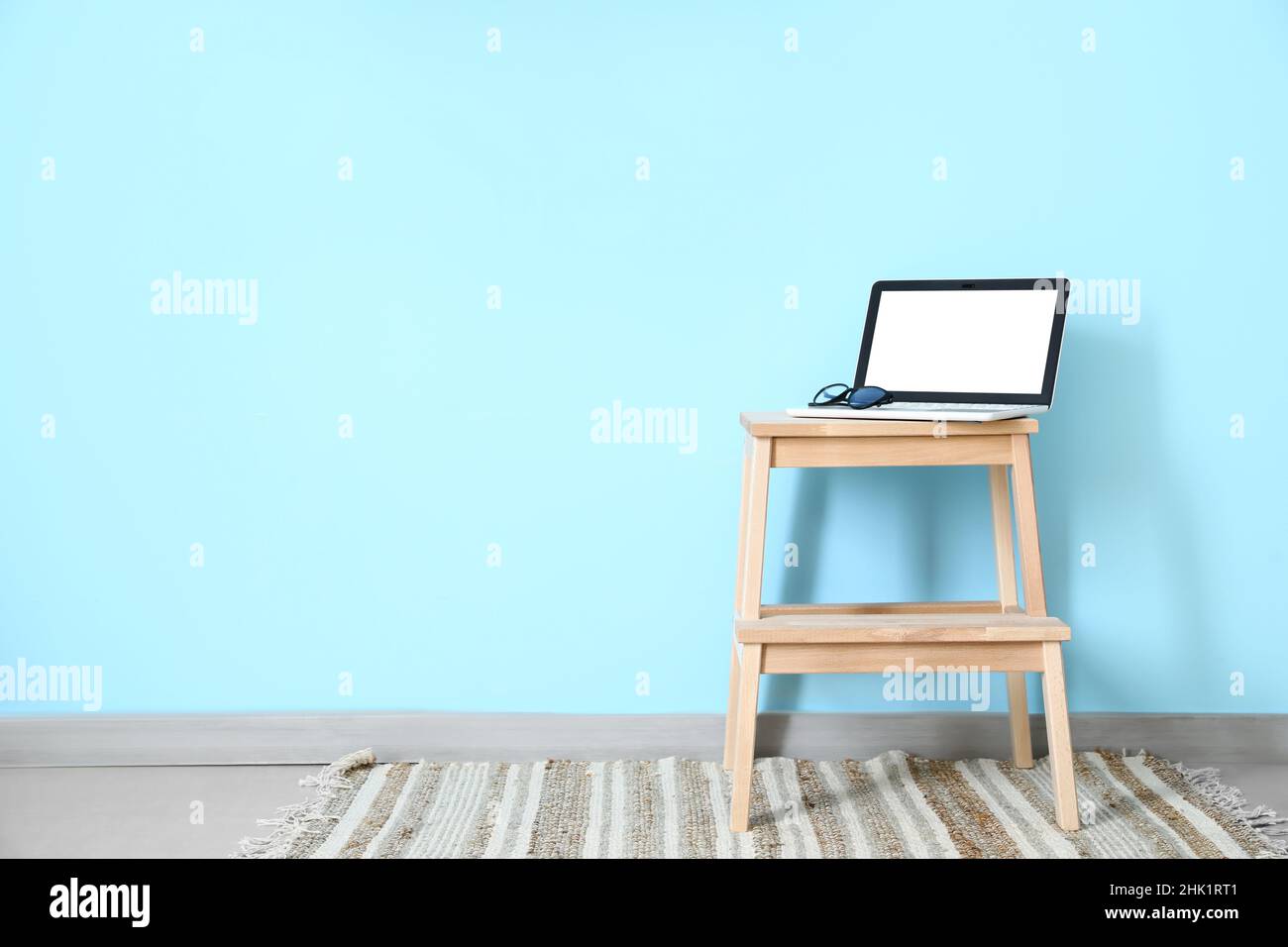 Wooden step stool with laptop near blue wall Stock Photo - Alamy