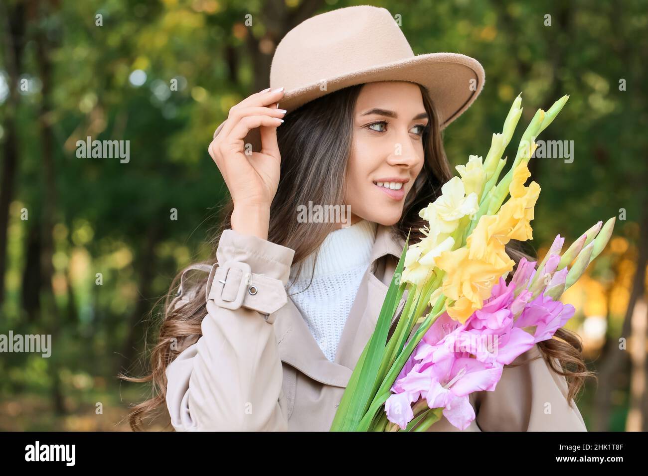 Woman wearing stylish felt hat and holding bouquet of Gladiolus flowers ...