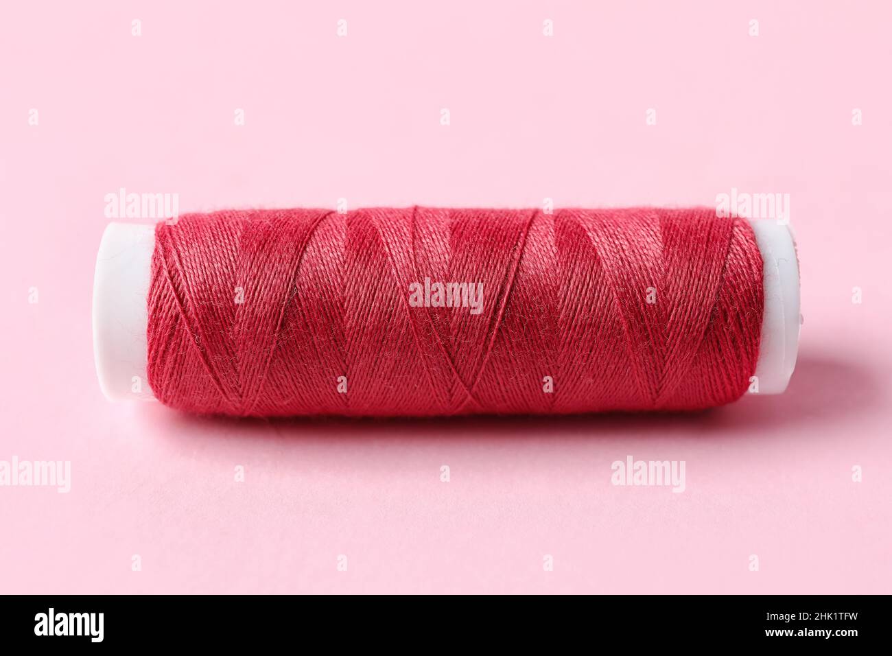 Red sewing thread spool on color background Stock Photo - Alamy