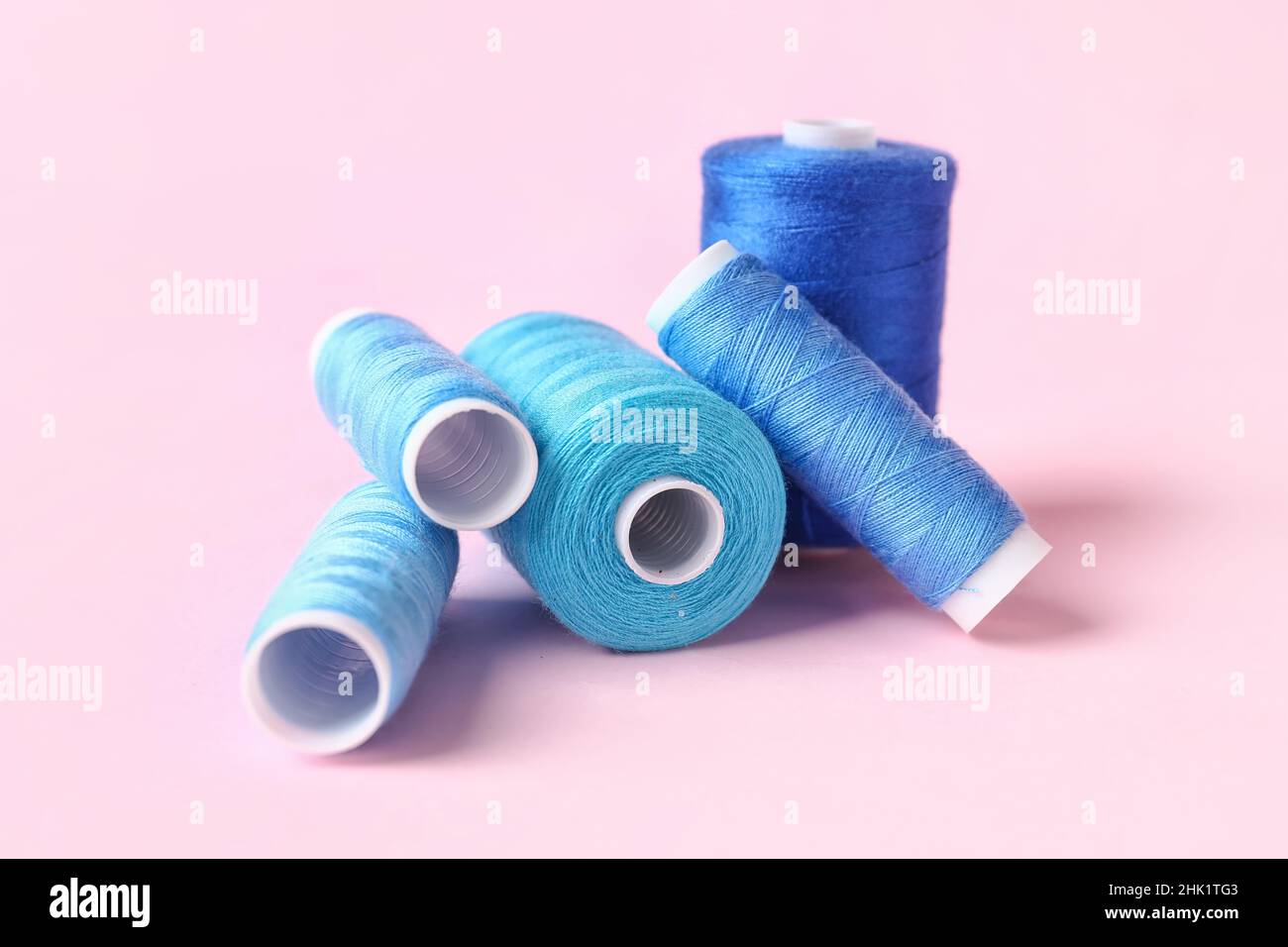 Blue sewing thread spools on color background Stock Photo - Alamy
