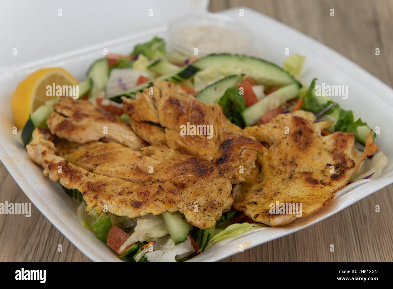 Take out order of grilled chicken salad completely filling the ...