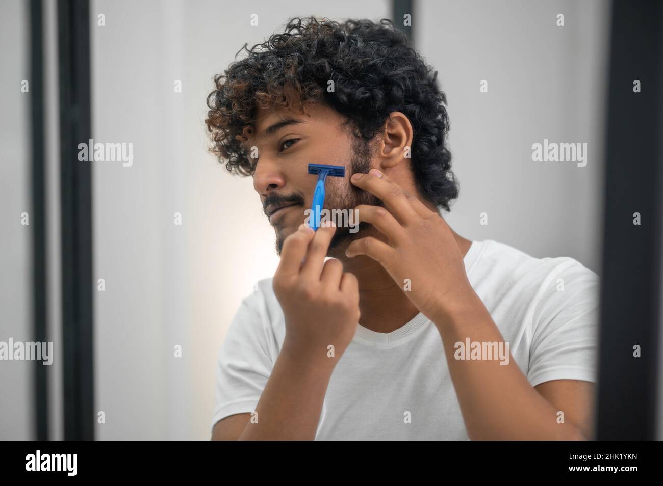 Focused guy using his safety razor for facial hair removal Stock Photo ...