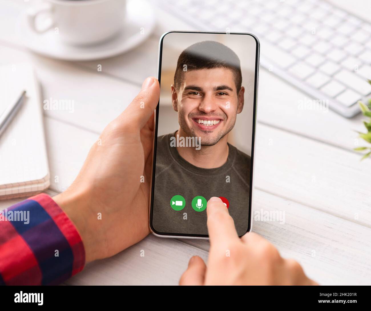 Man having video call with friend, sitting at workplace and holding ...