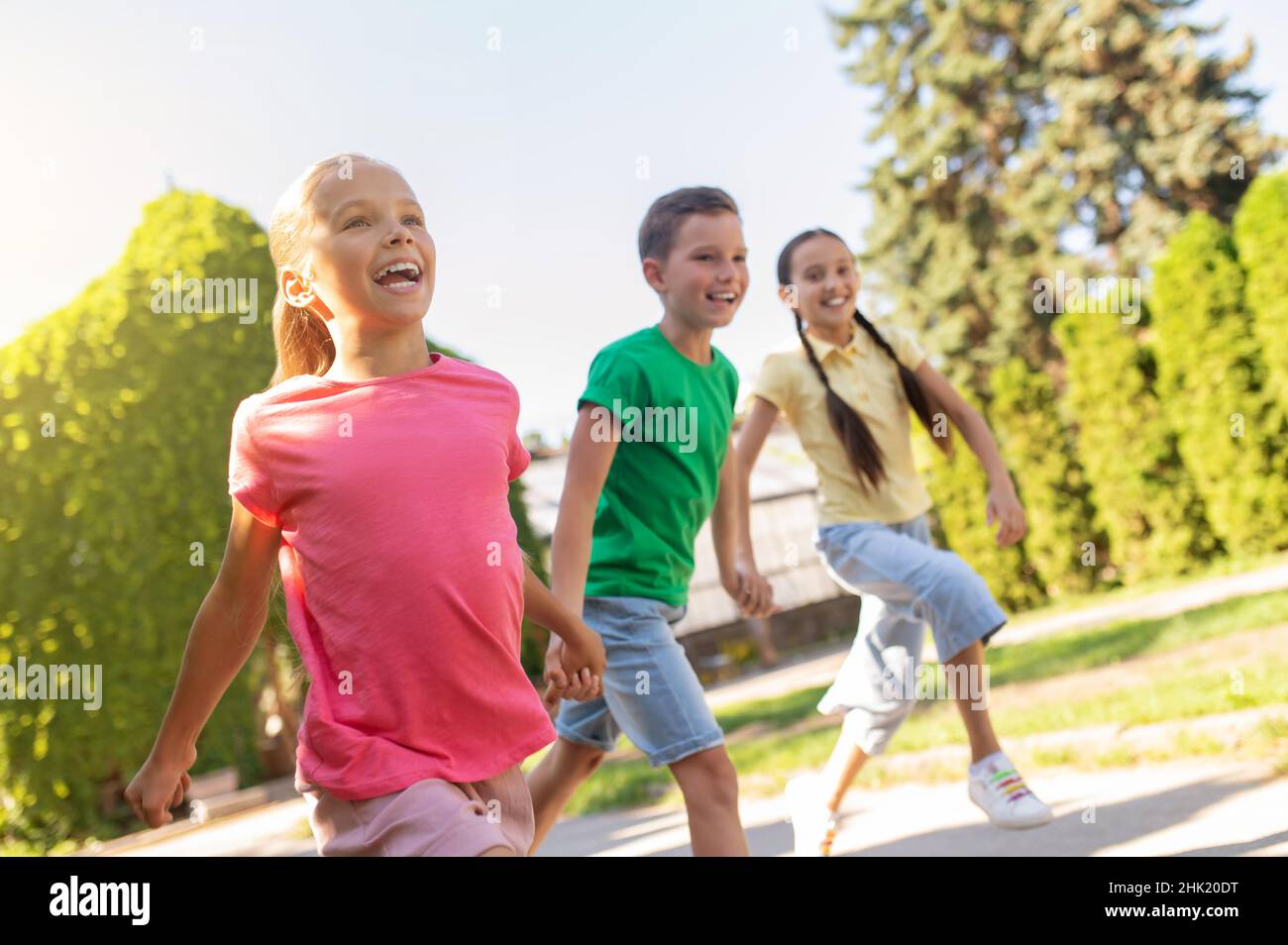 Boy and two girls running hand in hand Stock Photo - Alamy