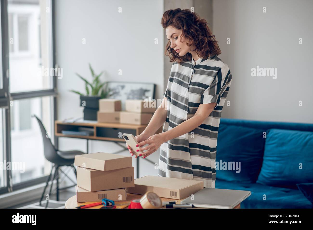 Worker aiming her smartphone camera at the product package Stock Photo ...