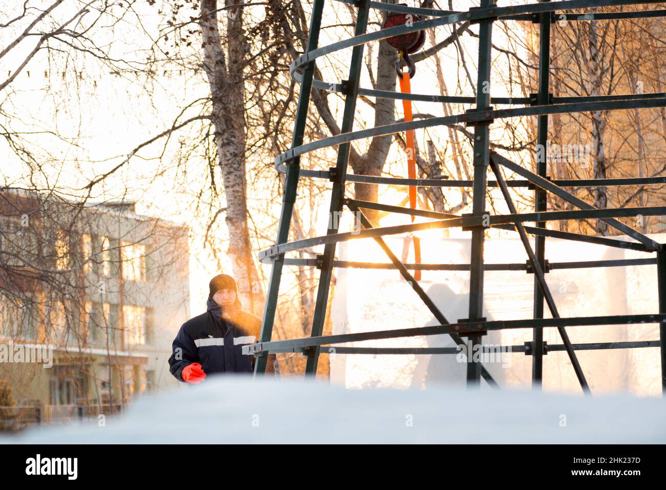 An ice town builder in a blue jacket encloses a Christmas tree under ...