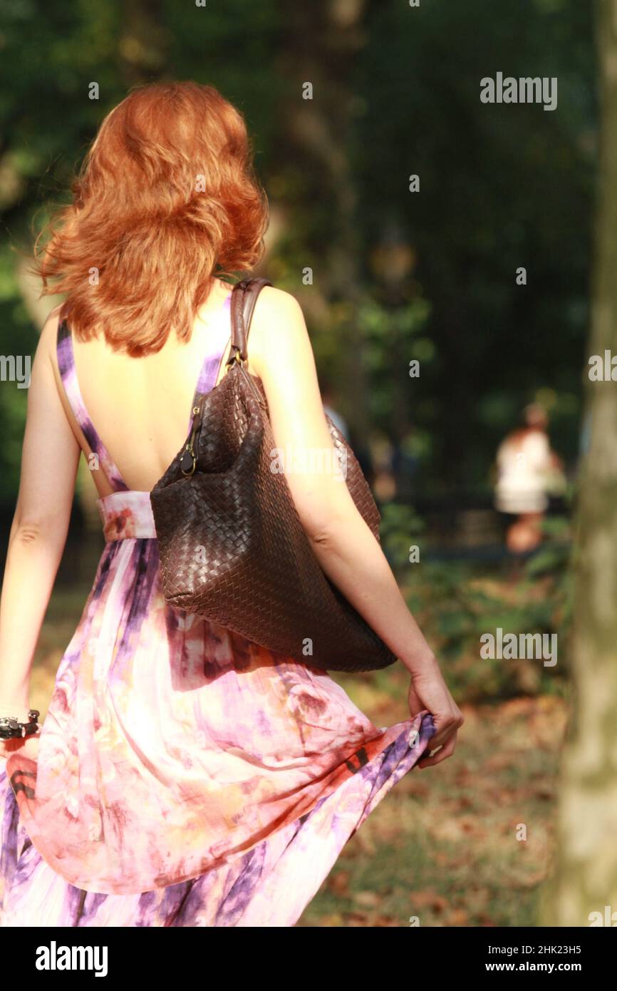 Portrait of a back of a female wearing a dress and a shoulder bag ...