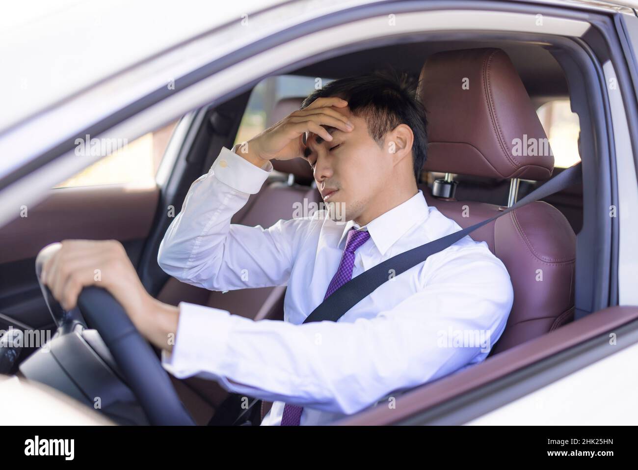 Sick, tired business man driving the car and waiting in traffic jam ...