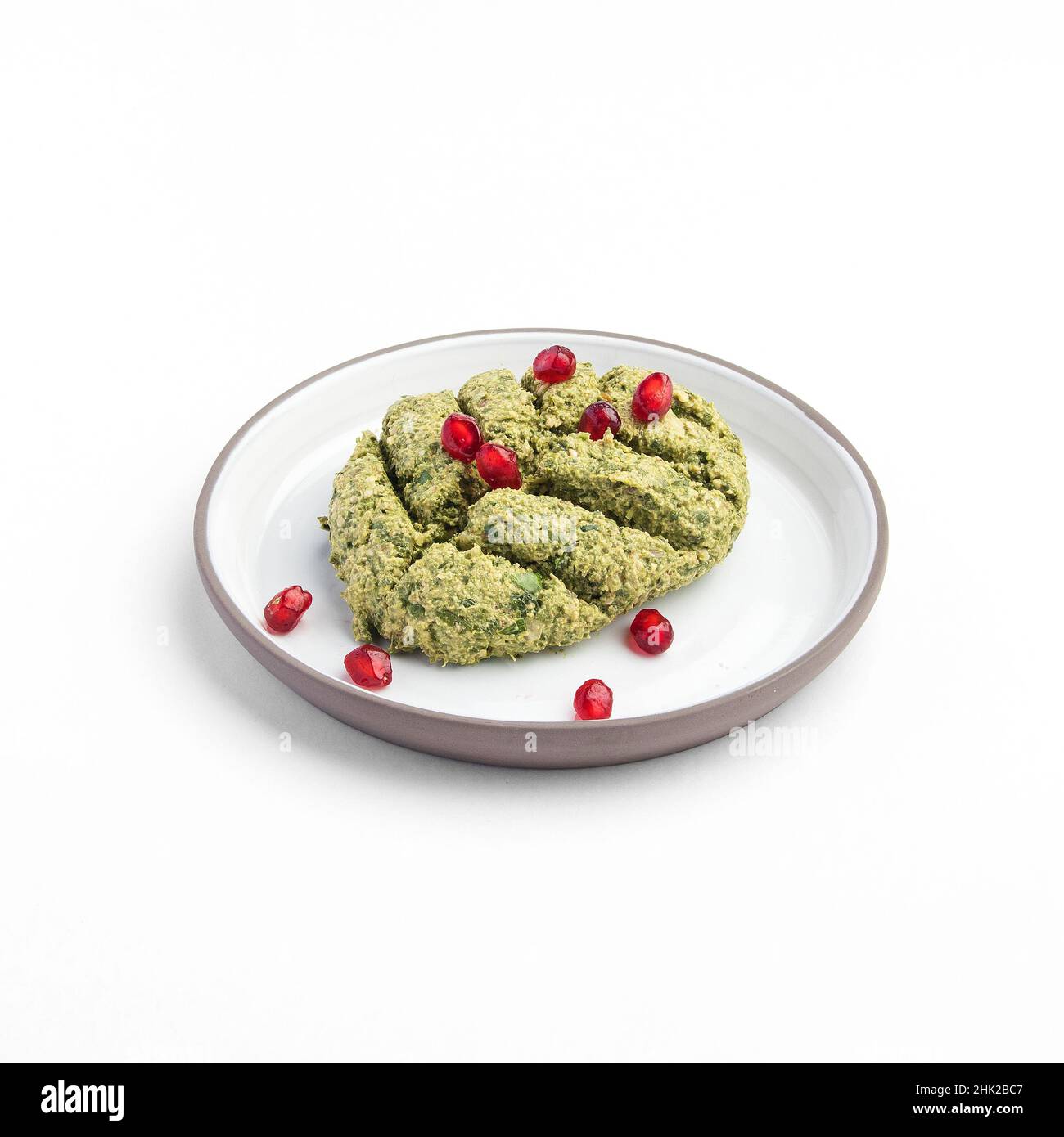 Plate of spinach pkhali decorated with garnets isolated on white ...
