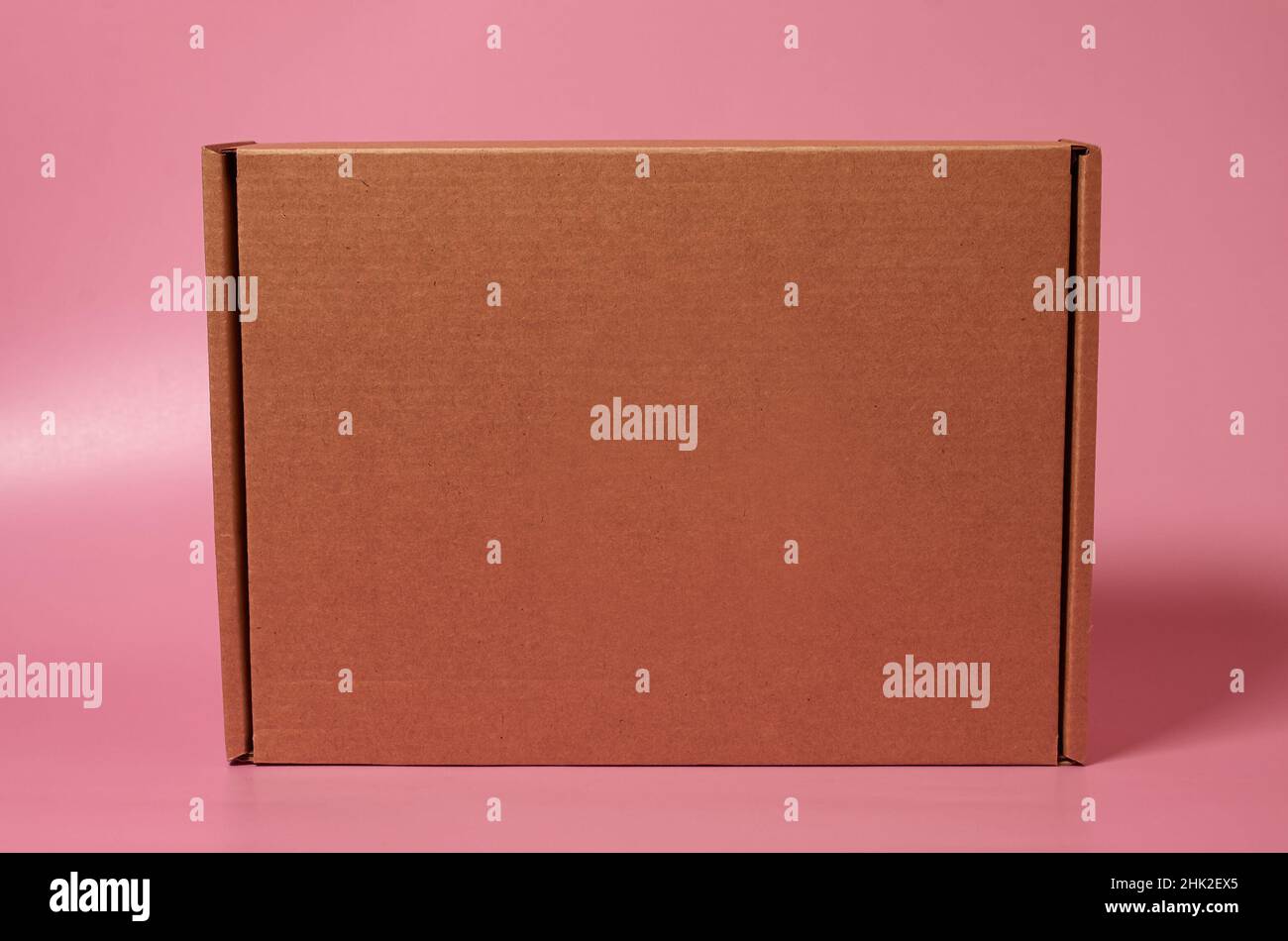 Closed cardboard box on a solid pink background Stock Photo - Alamy