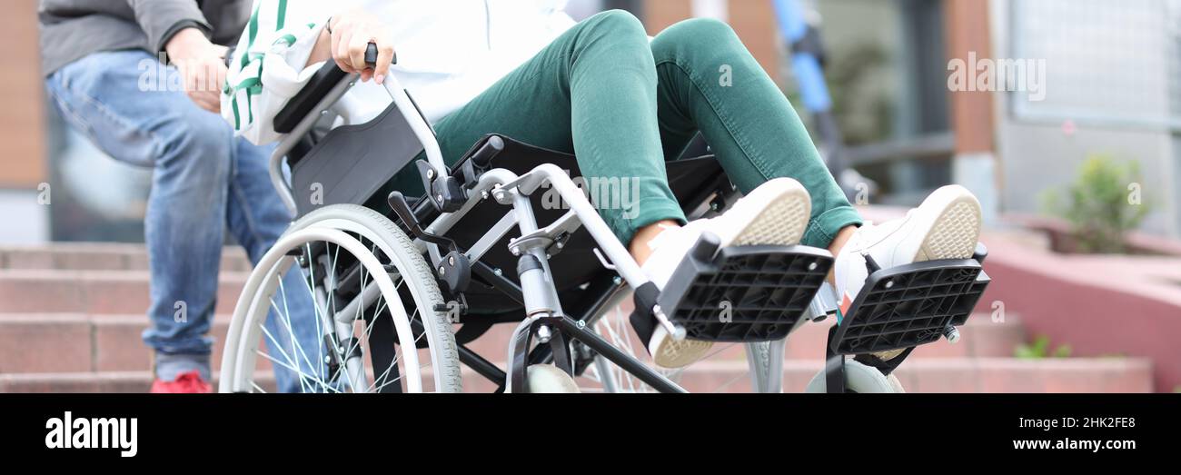 Man lifts wheelchair up steps with woman closeup Stock Photo - Alamy