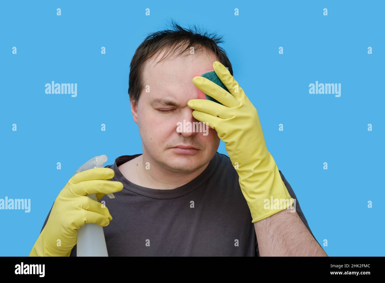 Sad male cleaner in yellow gloves, studio blue background Stock Photo ...