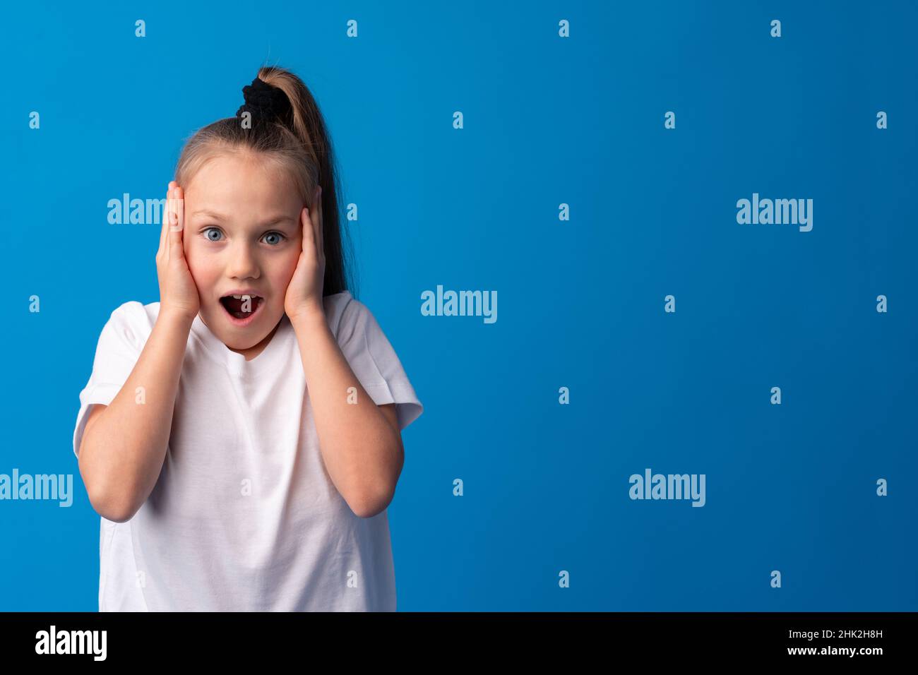 Shocked little girl looking with amazement on blue background Stock ...