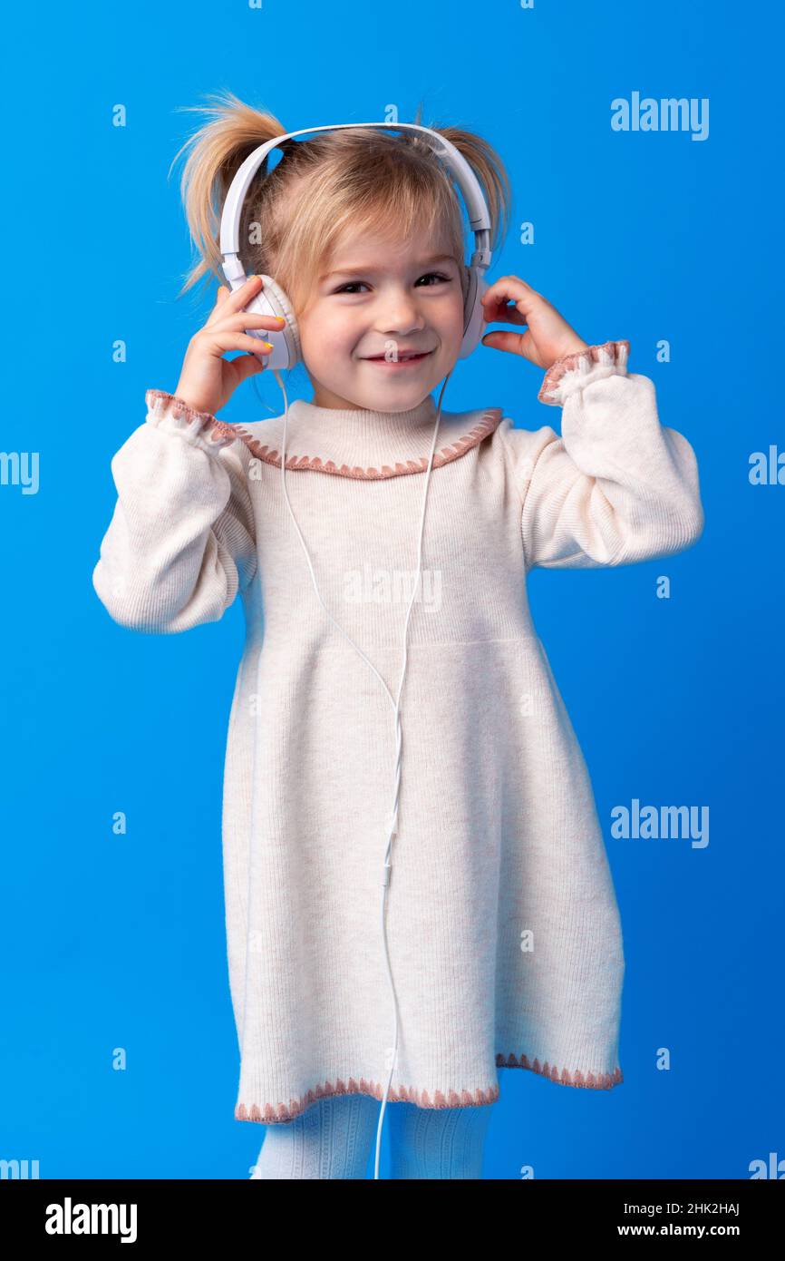 Little girl child wear headphones listen to music over blue background ...