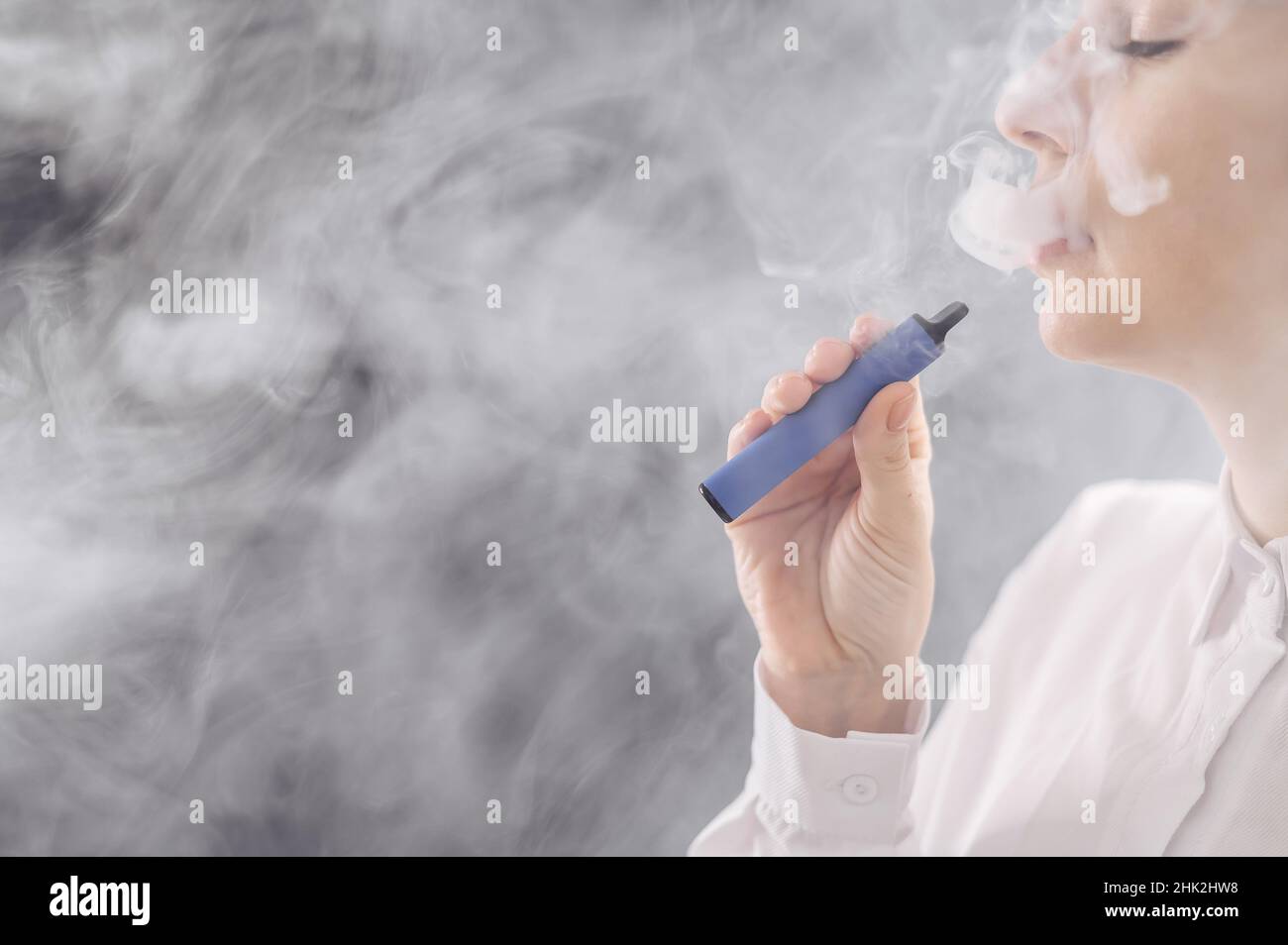 Caucasian woman smokes a disposable vape in the studio Stock Photo - Alamy