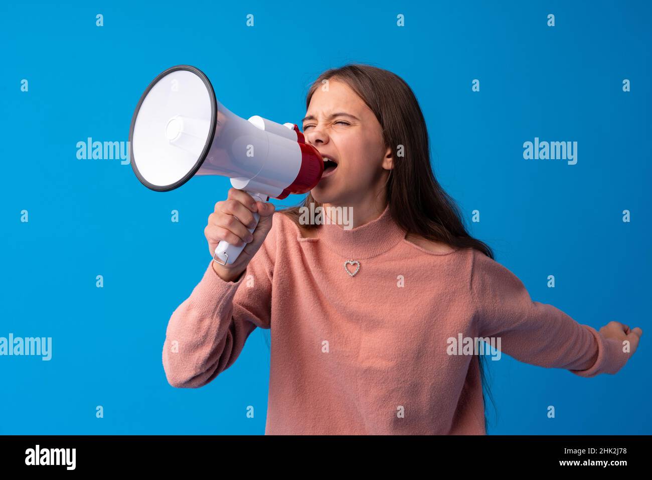 Teen girl making announcement with megaphone at blue studio Stock Photo ...