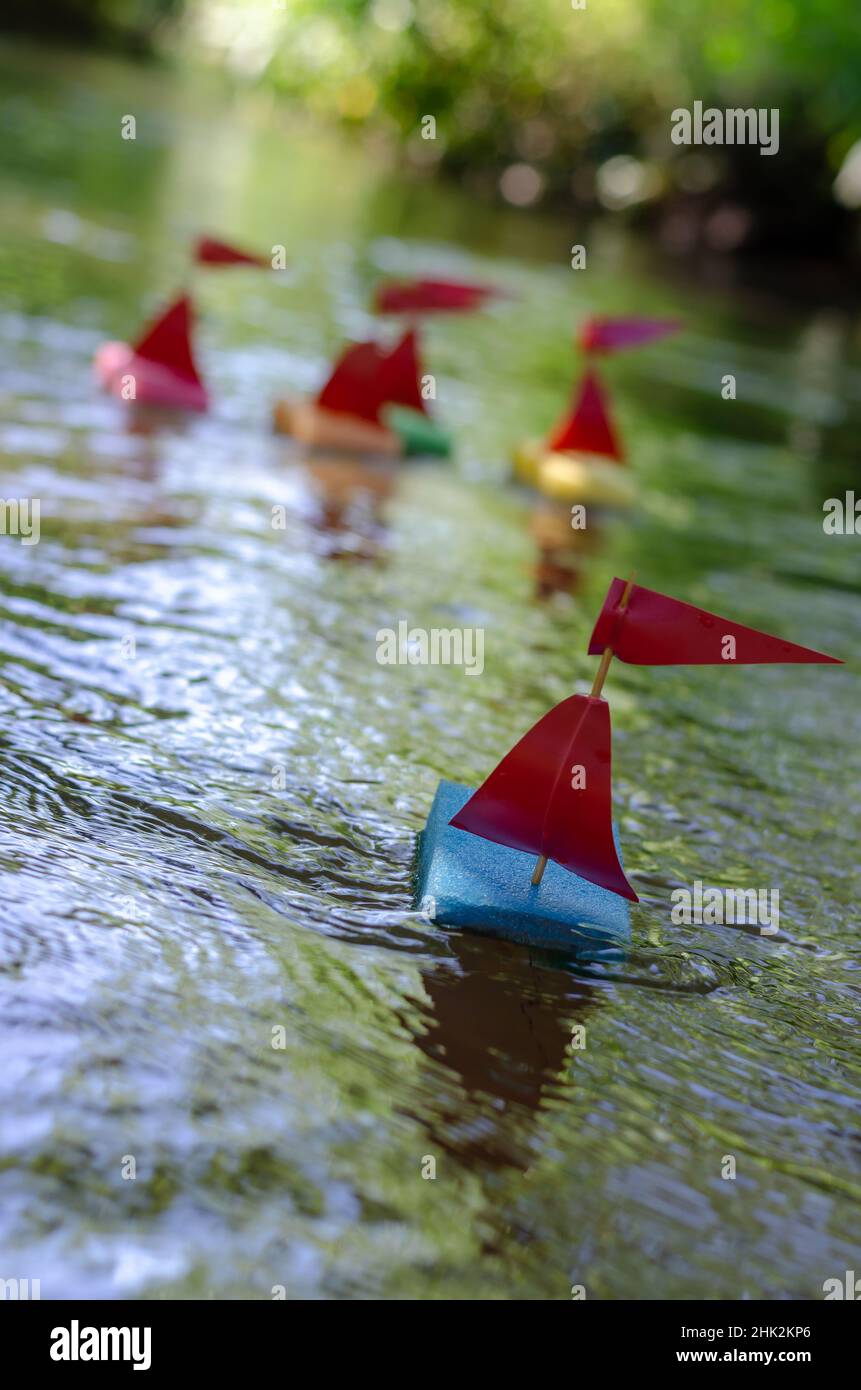 Children's boats are floating on the narrow river. Homemade mast boats ...