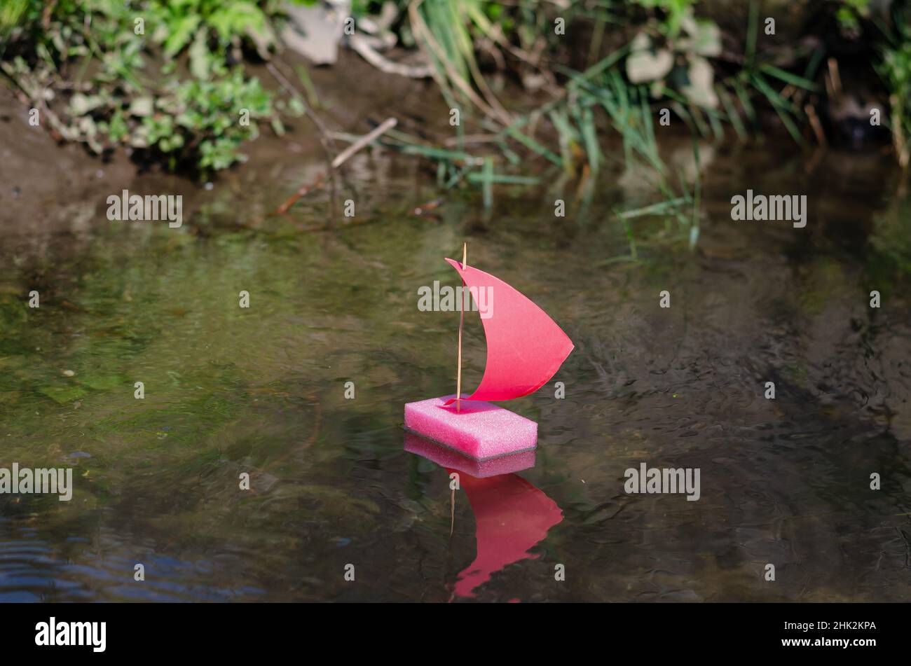 A pink sailboat floats on the pond. The ship is made from a kitchen ...