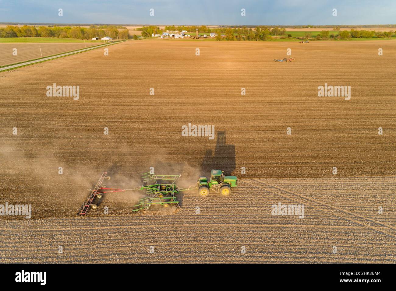 Aerial view of tractors working the soil before planting at sunset ...