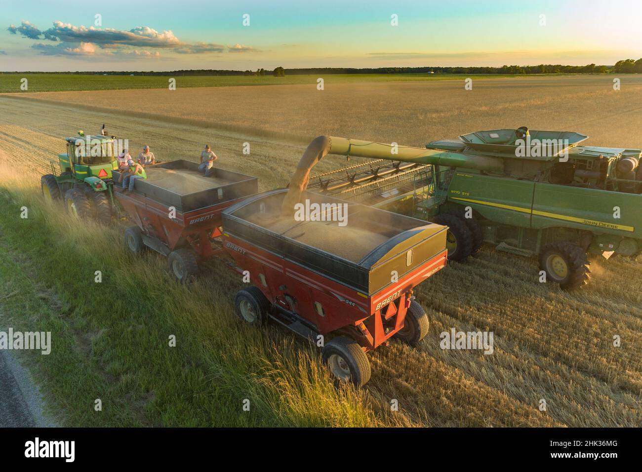 Aerial view of combine and unloading wheat into gravity wagons at ...