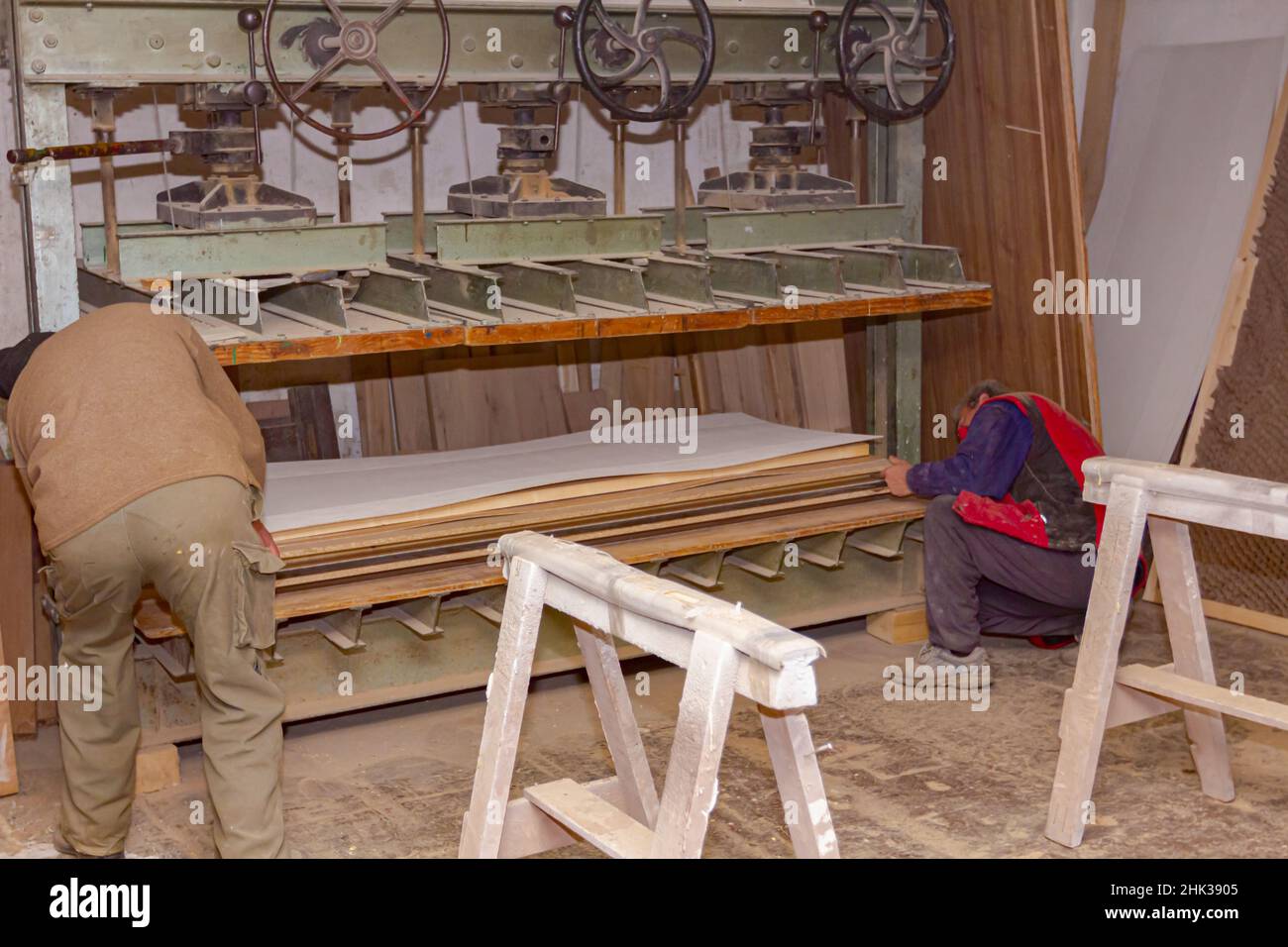 Carpenter workers are putting wooden profiles smeared with glue in the ...
