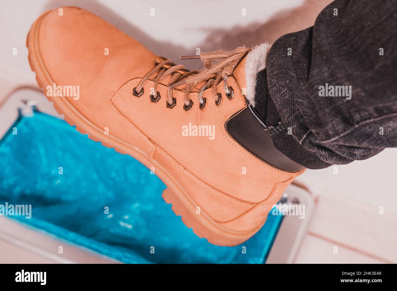 Device for automatic dressing of boot covers, a man in brown shoes puts ...