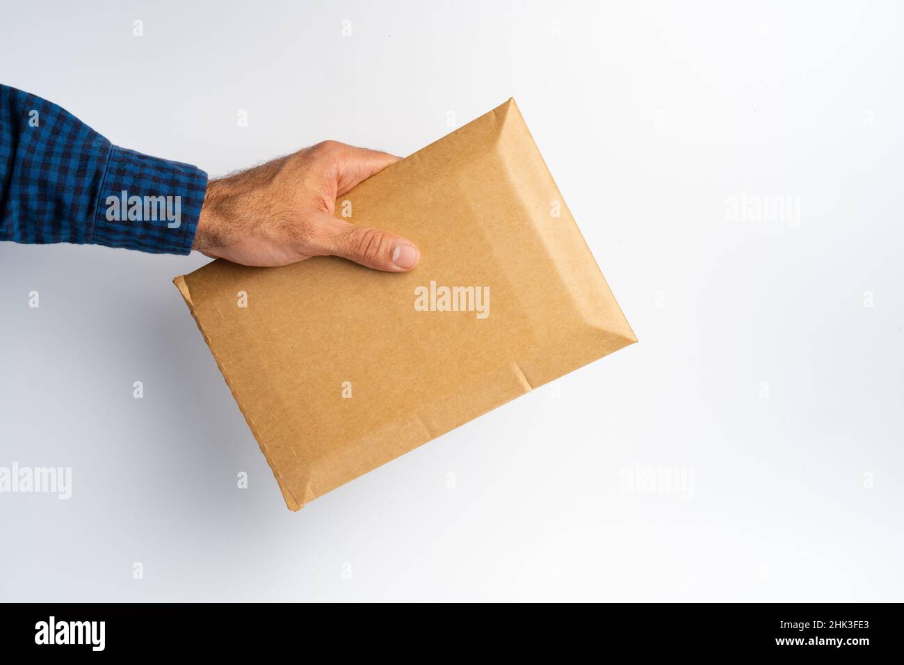 Male hand holding parcel post against white background Stock Photo - Alamy