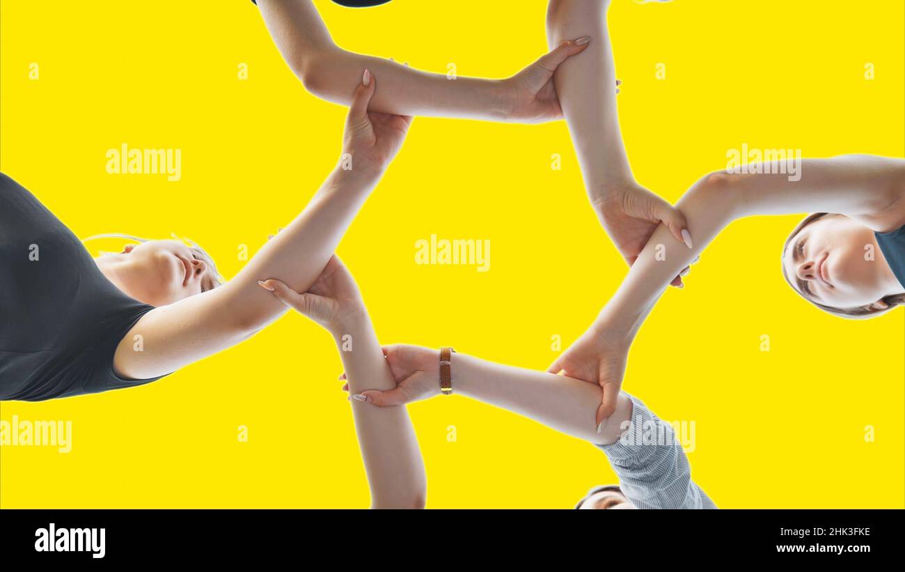 Friends join their wrist and make a circle on a yellow background ...