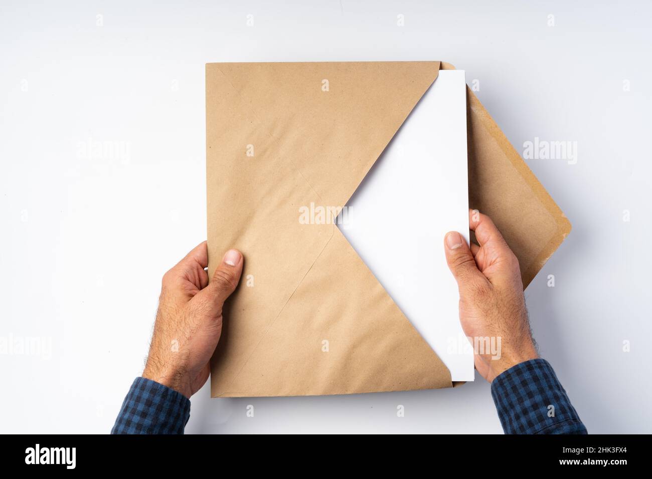 Top view of male hands hold (open) an envelope above white background ...
