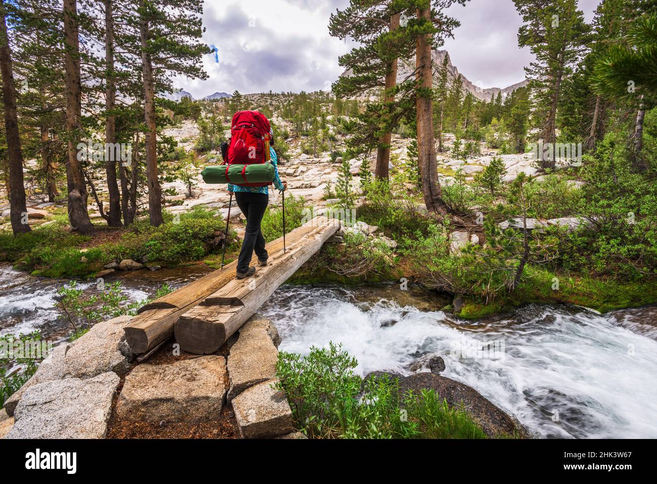 Backpacker crossing creek in the John Muir Wilderness, Sierra Nevada ...