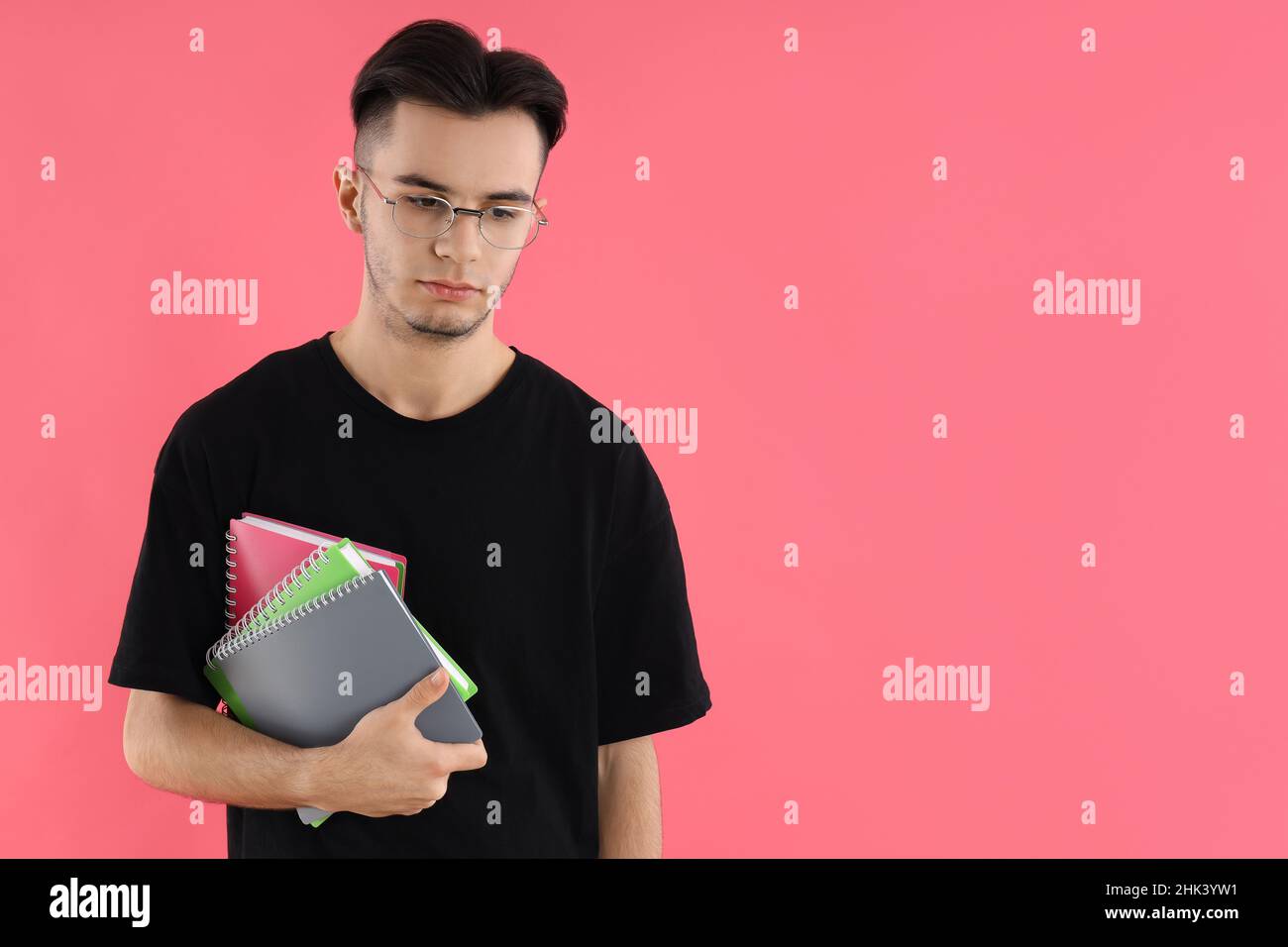 Male student with notebooks on pink background Stock Photo - Alamy