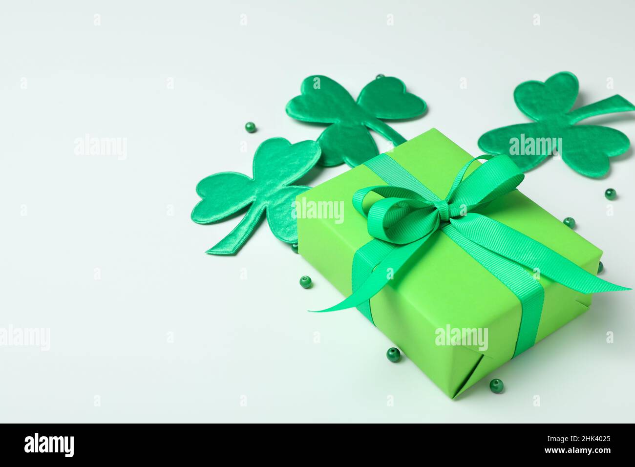 Clover leaves, gift box and beads on white background Stock Photo - Alamy