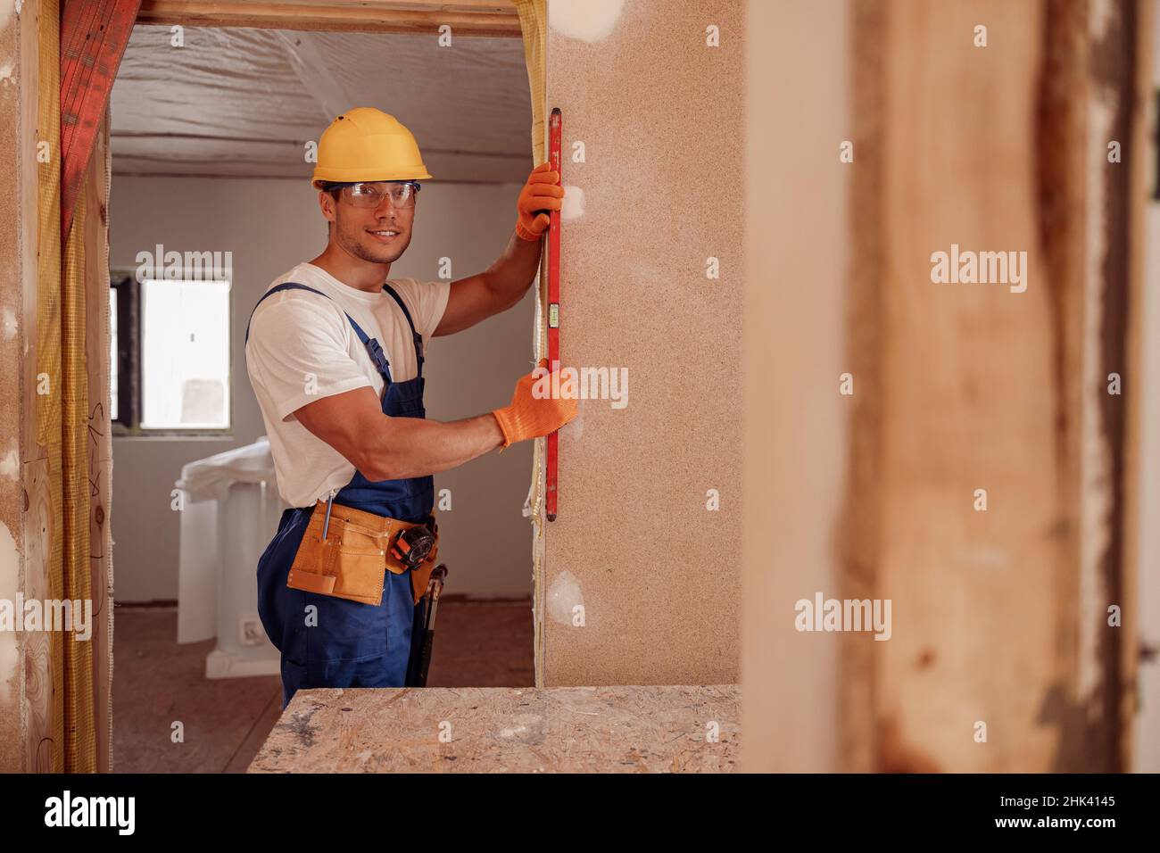 Cheerful male worker measuring wall in house Stock Photo - Alamy